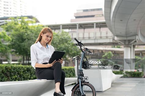 태블릿을 사용하여 자전거를 들고 사무실 건물 밖에 앉아 있는 사업가 자전거로 출퇴근하는 여성은 시내로 출근합니다 친환경 차량 지속 가능한 라이프스타일 컨셉 감소에 대한 스톡