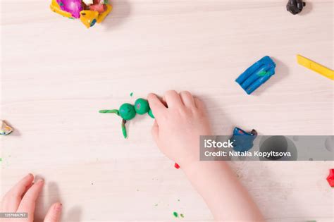 작은 아이가 나무 테이블에 녹색 플라스틱에서 애벌레를 조각 집에서 아이를 즐겁게하는 것보다 손의 미세 한 운동 기술의 개발