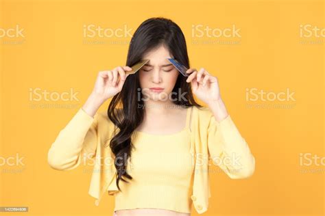 아시아 여성은 노란색 배경에 스트레스를 받고 파산하고 화가 나고 좌절감을 느끼며 신용 카드를 들고 눈을 감습니다 신용 카드에