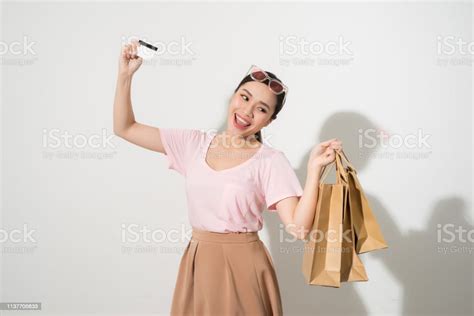 쇼핑 가방을 들고 깜짝 행복 한 소녀의 초상화와 흰색 배경 위에 고립 된 카메라를 보면서 신용 카드를 보여주는 가방에 대한 스톡