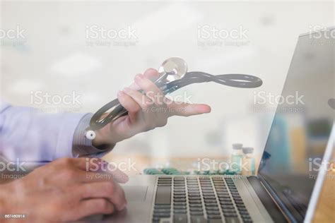 의사 의사가 자신의 컴퓨터에 의료 기록을 보여주는 청진기를 들고 그는 병원 인테리어와 클리닉 이중 노출의 화면을 가리키고있다