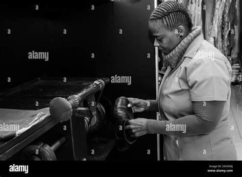 A Grayscale Shot Of An African Woman Working In A Shoe Repair And Dry