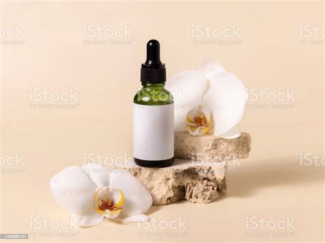 밝은 노란색에 흰색 난초 꽃 근처의 녹색 점적기 유리 병 모형 스킨케어 제품 0명에 대한 스톡 사진 및 기타 이미지 0명