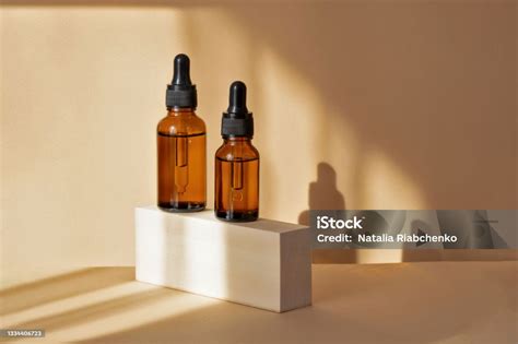 햇빛에 나무 선반에 서 두 유리 드롭퍼 병의 모형 프리젠 테이션을위한 즉석 기하학적 받침대 화장품 포장 시연을 위한 3d 연단