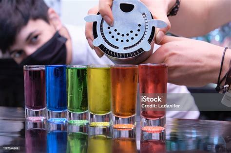 술집에서 Lgbt 컬러 샷을 준비하는 보호 얼굴 마스크를 착용한 인식할 수 없는 웨이트리스 바에 대한 스톡 사진 및 기타 이미지