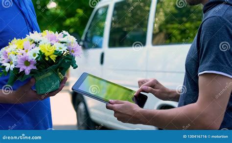 Man Appending Signature On Tablet And Receiving Flower Present From