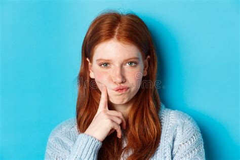Puzzled Redhead Girl Looking Suspicious At Camera Thinking Or Solving Problem Standing Against