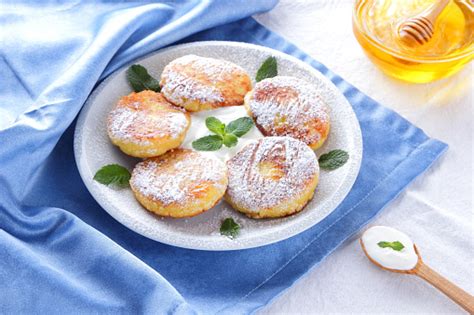 코 티 지 치즈 뿌려 가루 설탕과 신선한 민트 팬케이크 흰색 접시에 치즈입니다 나무로 되는 숟가락에 사 우 어 크림입니다 흰색