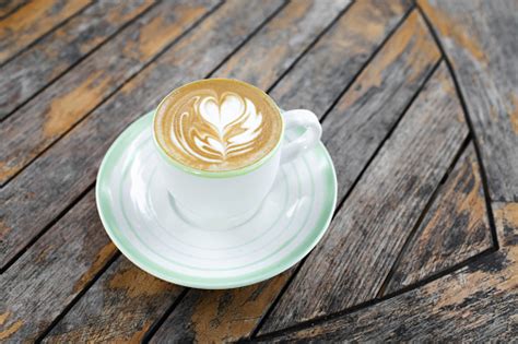 거품에 라떼 아트와 신선한 크리미 한 카푸치노 컵 초라한 숙성 된 표면갈색 나무 테이블의 배경입니다 위에서 볼 수 있습니다