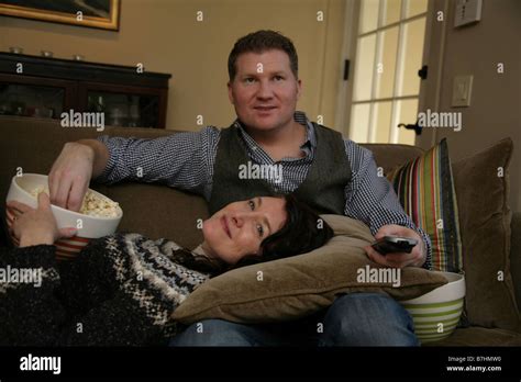 A Couple Relaxing And Snacking While Watching Tv On Their Living Room