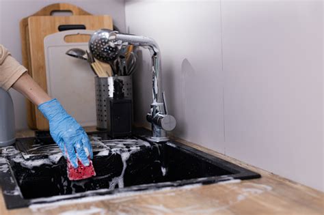 파란 장갑을 낀 분홍색 스펀지로 나무 위에 식기와 조리기구를 놓고 위생과 설거지에 집중하며 부엌 싱크대를 청소하는 사람 가사 집안일에 대한 스톡 사진 및 기타 이미지