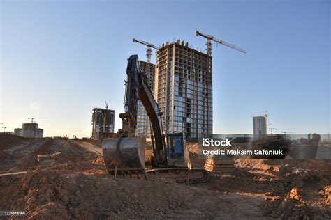 토목 공사 현장에서 작업하는 굴삭기 도로 공사에 백호는 땅을 파고 하수도 라인을 포장합니다 화물의 굴착 적재 리프팅 및 운반을 위한 건설 기계 개발에 대한 스톡 사진 및