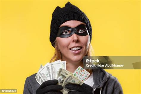 사이버 범죄 및 돈 도난 모자 장갑 가면을 쓴 한 여성이 손에 돈을 들고 꿈꾸며 위를 올려다본다 노란색 배경입니다 복사 공간 개념에 대한 스톡 사진 및 기타 이미지 Istock