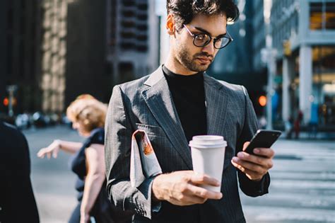 안경을 쓴 젊은 남성 기업가는 도시 거리에 서 있는 휴대전화로 메시지를 받은 뉴스를 받고 우아한 정장을 입은 사업가와 현대 셀룰러에서 알림을 확인하는 안경을 쓰고 있다 30