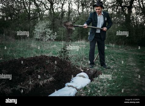 Maniac With A Shovel Buries Victim Into A Grave The Body Wrapped In A