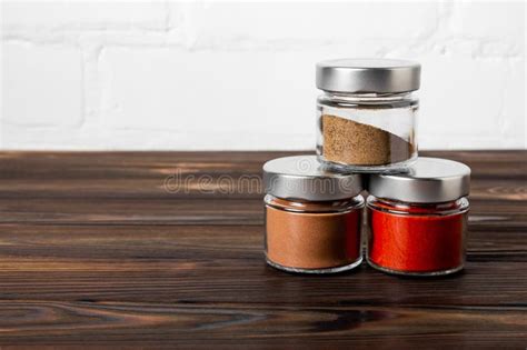 Bright Fragrant Spices In Glass Jars Of Different Sizes On A Wooden