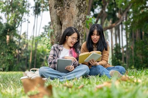 Premium Photo Two Young Asian Female Students Sit On The Grass Under