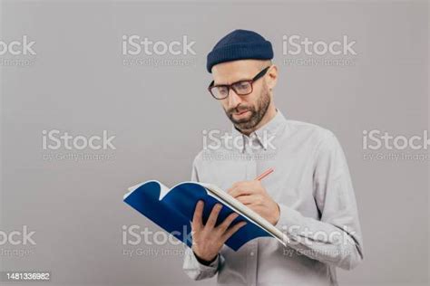 심각한 남성 교사는 다음 수업에 대 한 메모를 씁니다 메모장을 보유 하 고 흥미로운 작업을 준비 하는 학생 들을 위한 공식적인 옷을 착용 텍스트 복사 공간 오른쪽에 회색