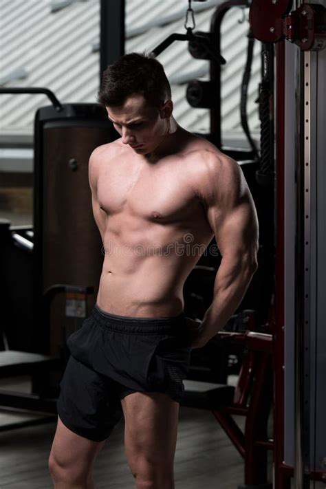 Hombre Muscular Hermoso Que Dobla Los Músculos En Gimnasio Foto de