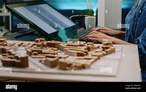 Close Up Of Building Model On Table And Woman Using Touch Screen Analyzing Maquette On Computer