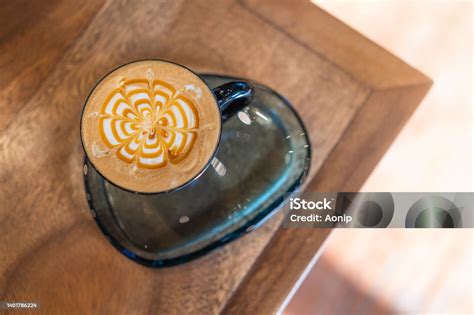 커피 숍에서 커피 라떼 컵의 최고 전망 복사 공간과 햇빛 배경이있는 카페의 나무 테이블에 검은 머그잔에 캐러멜 아트가있는 뜨거운 마키아토 커피 갈색에 대한 스톡 사진 및