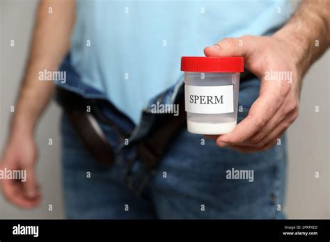 Donor With Unzipped Pants Holding Container Of Sperm Closeup Stock