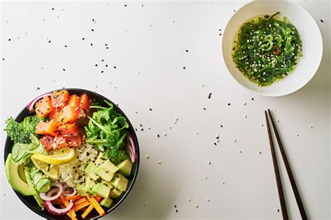 연어 아보카도 오이 Arugula 브로콜리 쌀 당근 달콤한 양파 華 샐러드 흰색 배경 위에 절연 젓가락으로 그릇을 찌른 상위 뷰