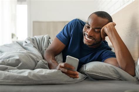 Premium Photo Black Guy Texting On Cellphone Browsing Internet Lying