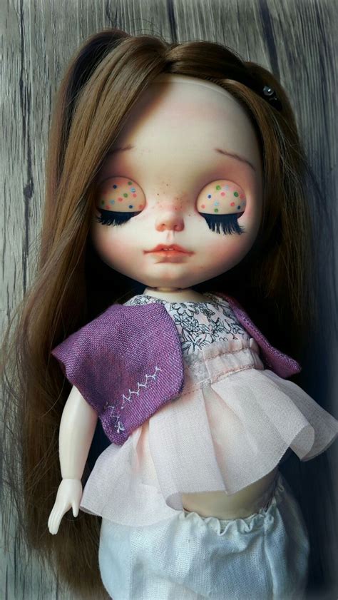 A Doll With Long Brown Hair Wearing A Purple Dress And Pink Eyeliners