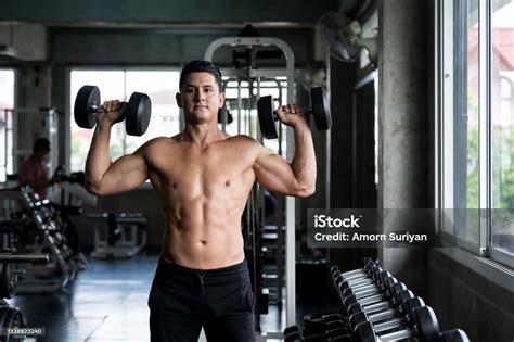 잘 생긴 남자 피트 니스 체육관에서 아름 다운 근육 리프팅 아령서서 서 스포츠 센터에서 운동하는 남자 남자는 자신의 건강 아령을