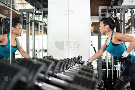 年轻女子在健身房选择哑铃。