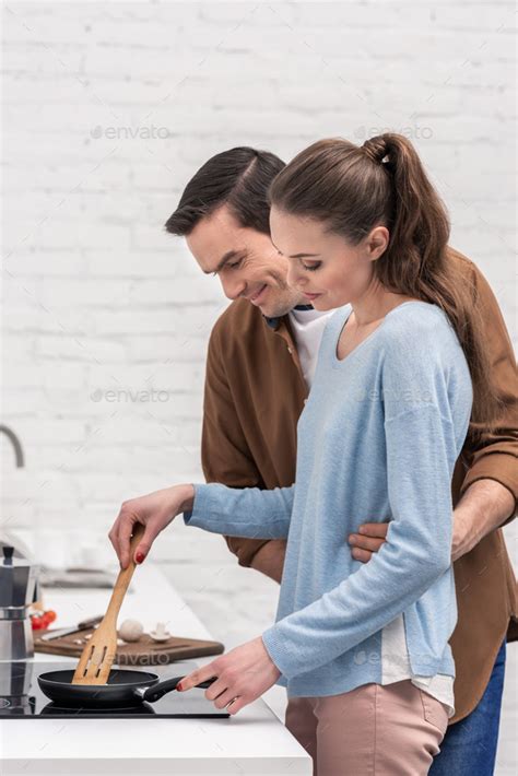 Happy Husband Embracing His Wife From Behind While She Cooking Stock