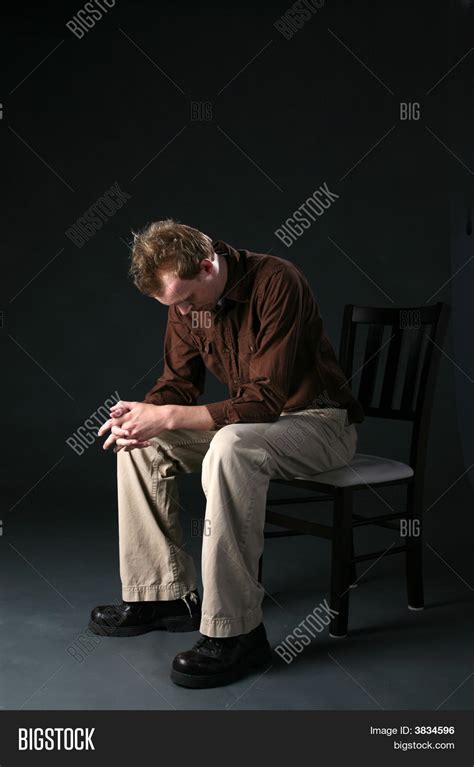 Man Sitting In Chair With Head Down Looking Sad Stock Photo Stock