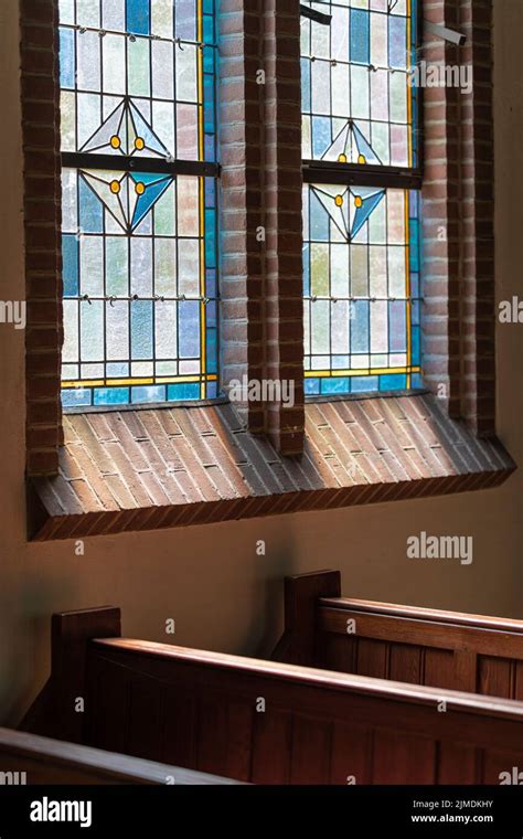 Wooden pews in an old Dutch church with a colorful stained glass window Stock Photo - Alamy