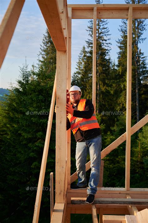 Carpenter Using Spirit Level While Constructing Wooden Frame House