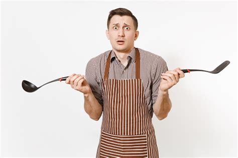 Bewildered 남자 요리사 또는 웨이터 스트라이프 브라운 앞치마 셔츠 검은 지주 국자 또는 부엌 숟가락 주걱 흰색 배경에