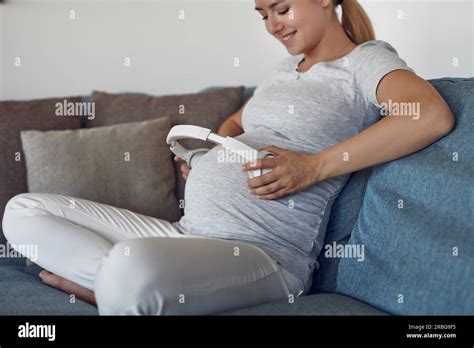 Smiling Happy Pregnant Young Woman Providing Music With Earphones To