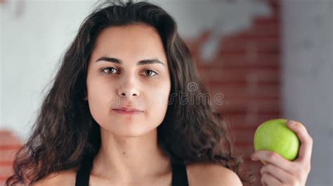 Close Up Face Of Hungry Beautiful Young Girl Having Perfect Skin Eating Apple Looking At Camera