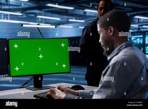 Focused Software Developer Working On Computer With Green Screen Monitor In Modern Data Center
