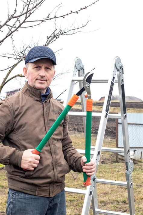 Pruning Trees In Spring Gardener With Big Shears In The Garden Near