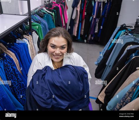 Top View Of A Chubby Cheeked Woman Holding An Armful Of Clothes In A
