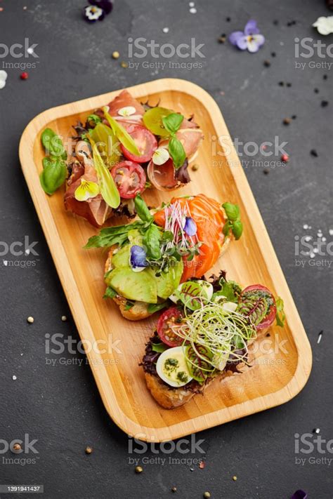 연어 파르마 및 페스토 수스로 구성된 모듬 브루 쉐타 세트 이탈리아 전채 간식 어두운 배경에 작은 샌드위치의 다양한 혼합