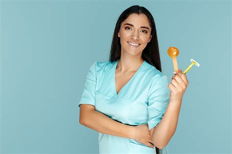 파란 배경 위에 탈포 절차를 위해 설탕 페이스트와 면도기를 들고 미소 짓는 미용사 개념에 대한 스톡 사진 및 기타 이미지