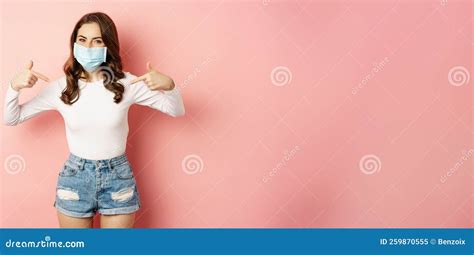 Young Woman In Medical Face Mask Pointing Fingers At Herself Showing
