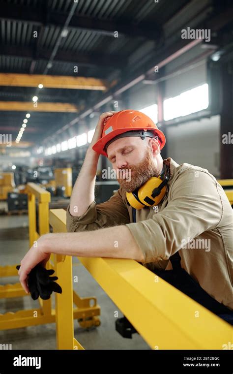 Tired Or Sick Engineer In Workwear And Hardhat Leaning By Bar While