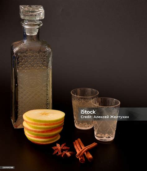 검은색 배경에 계피와 아니스를 곁들인 사과 리큐어 크리스탈 디캔터에 담긴 독한 홈메이드 알코올 잘 익은 과일과 향신료 조각이