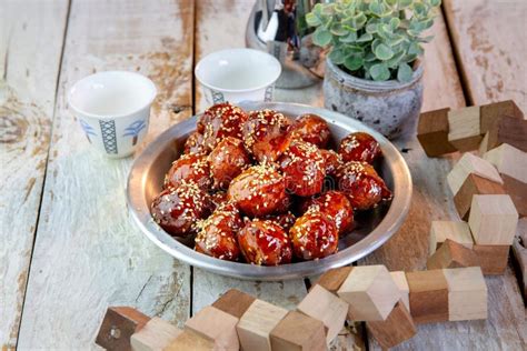 A Metal Plate Filled With Sesame Covered Food Next To Small Wooden