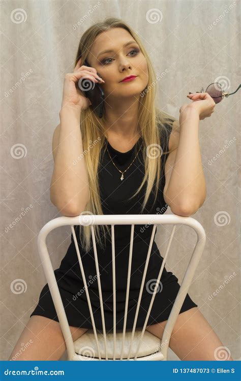 Beautiful Young Girl Sitting On A White Chair And Talking On A Cell