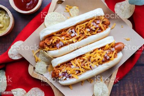 칠리 개 케첩과 겨자를 곁들인 나무 테이블의 나무 트레이에 담긴 칠리 치즈 핫도그 길거리 음식에 대한 스톡 사진 및 기타 이미지