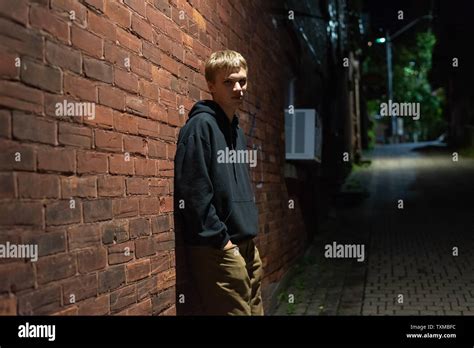 Serious Looking Teenager Leaning Against A Brick Wall In An Alleyway At